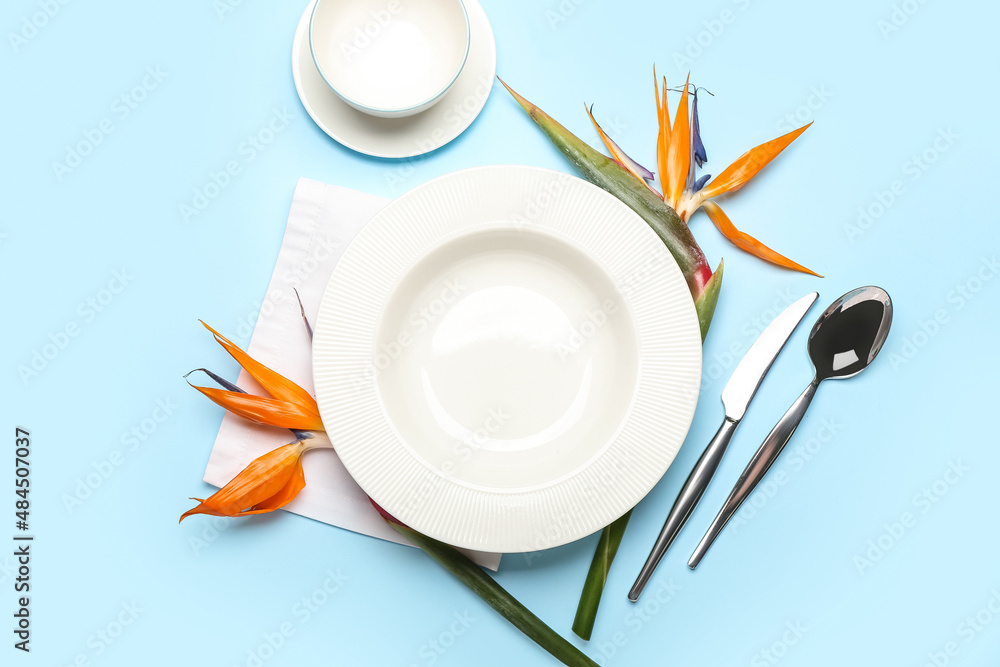 Simple table setting with bird of paradise flowers on blue background ...