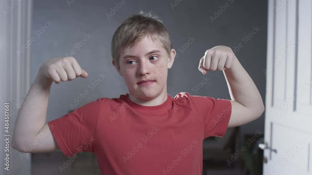 Portrait of a guy with down syndrome. The kid demonstrates muscles and ...