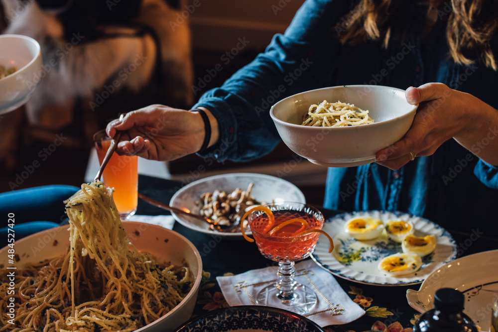 woman serving herself spaghetti noodles over table full of food Stock ...