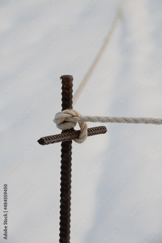 t shaped cross shaped metal rebar post with rope tied in knot around ...