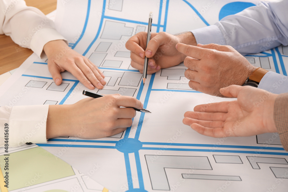 Professional cartographers working with cadastral map at table, closeup ...