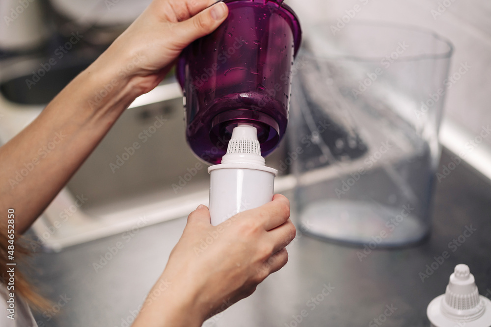 Woman replacing filter in a water pitcher. Female hand removes an old ...