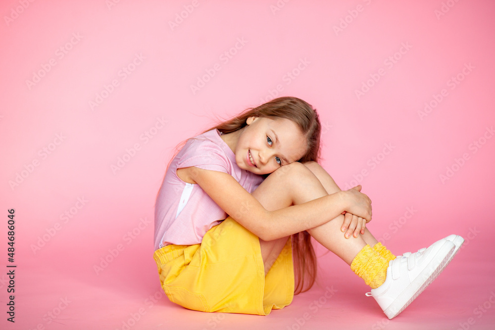 A funny little blonde girl of 10 years old in everyday bright clothes ...