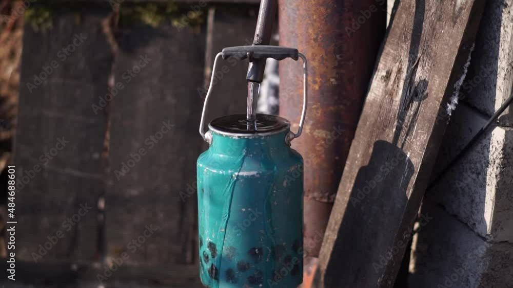 Clean drinking water from the artesian column flows into an old can and ...
