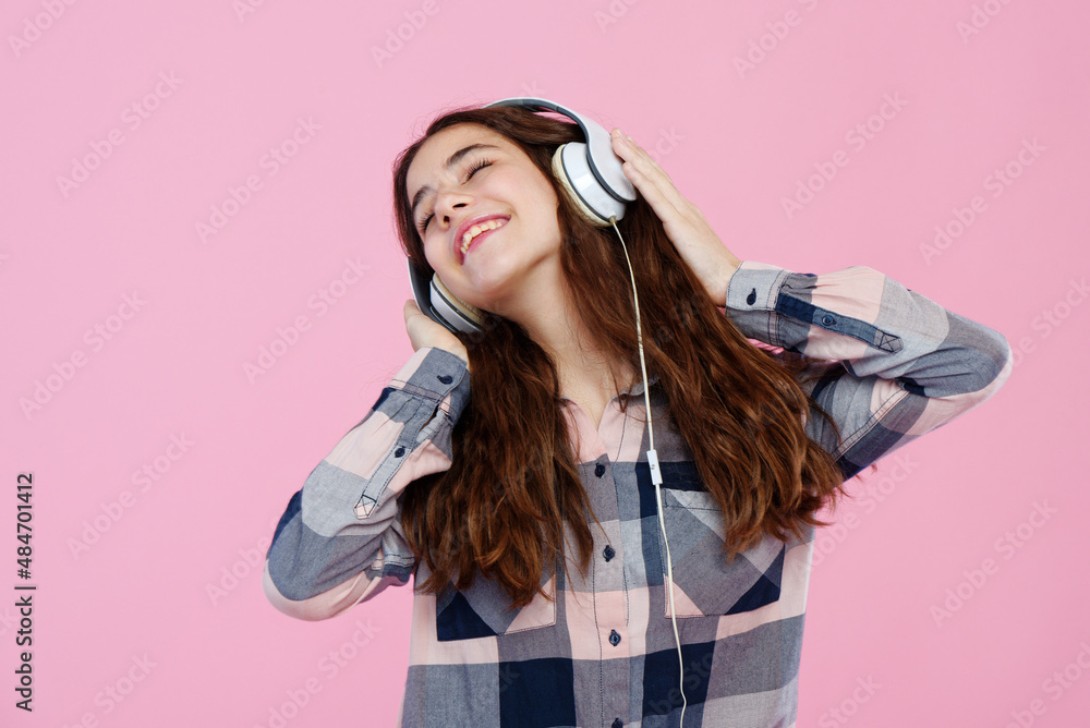 Sweet teenage girl listening to her favorite music on big earphones ...
