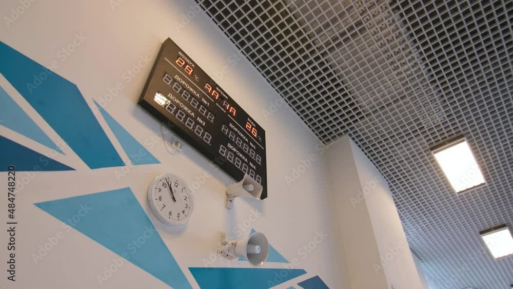 Digital scoreboard clock and loudspeakers on wall with blue pattern in ...