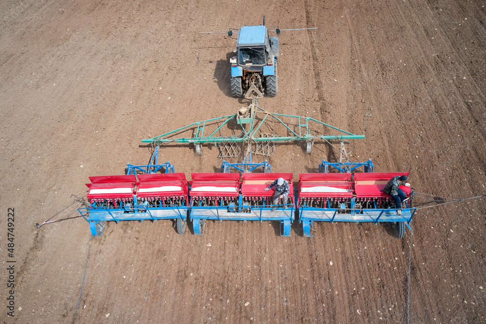 Tractor with a seeder on arable land. Grain and mineral fertilizer are ...