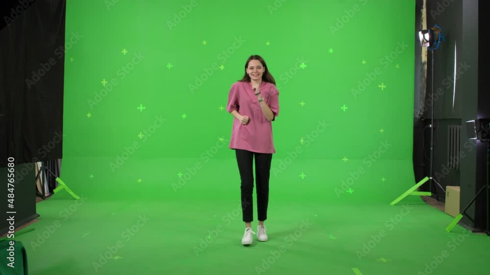 Young woman dancing on a green screen background. Girl makes a gesture ...