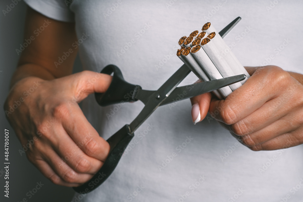 Woman cutting with scissors cigarettes. Stop smoking, quit smoking or ...