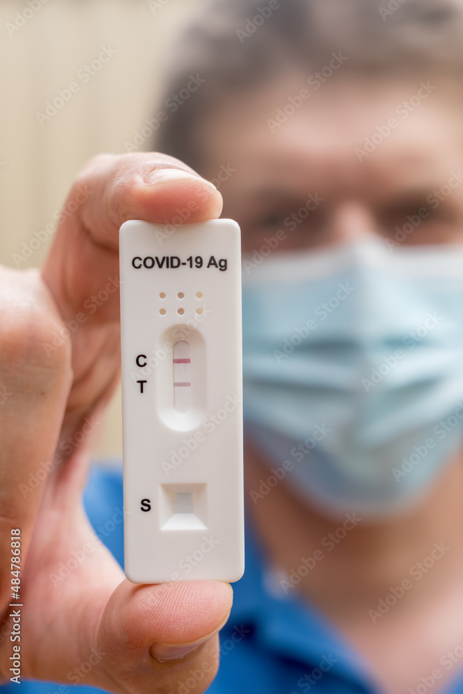 Man wearing face mask holding Covid-19 rapid antigen test cassette with ...