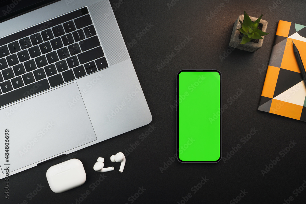 Smartphone with green screen on black background table. Office ...