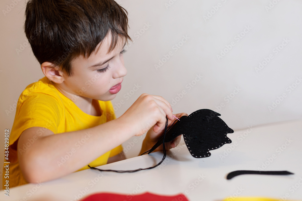 the boy is doing needlework. Sewing a soft toy from felt, hands close ...