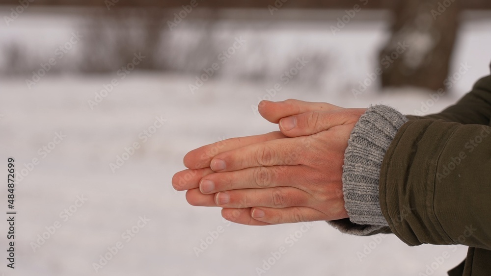 Close-up side view photography of two male hands isolated on cold snowy ...