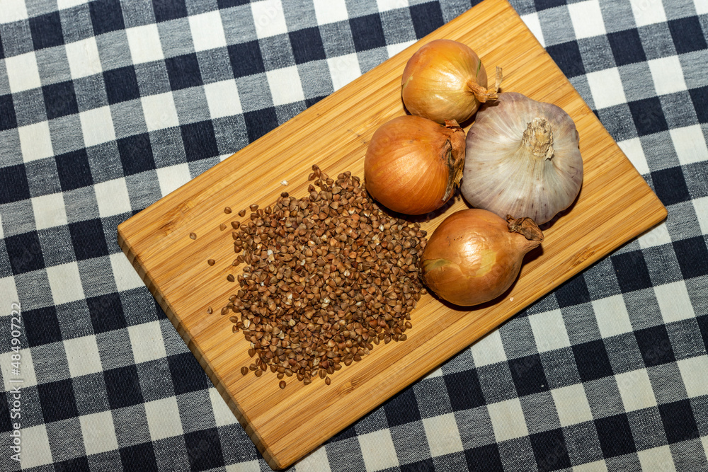 Vegetables and buckwheat on a board. Top view of buckwheat, onions and ...