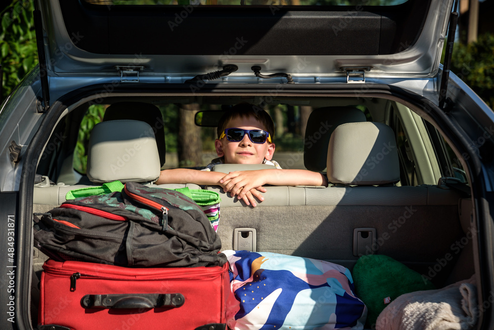 Adorable kid boy wearing sunglasses sitting in car trunk. Portrait of ...