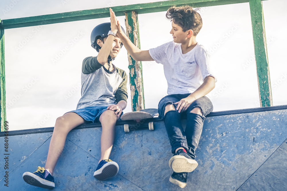 Two young boys hit high five after nice tricks and jumps at the ...