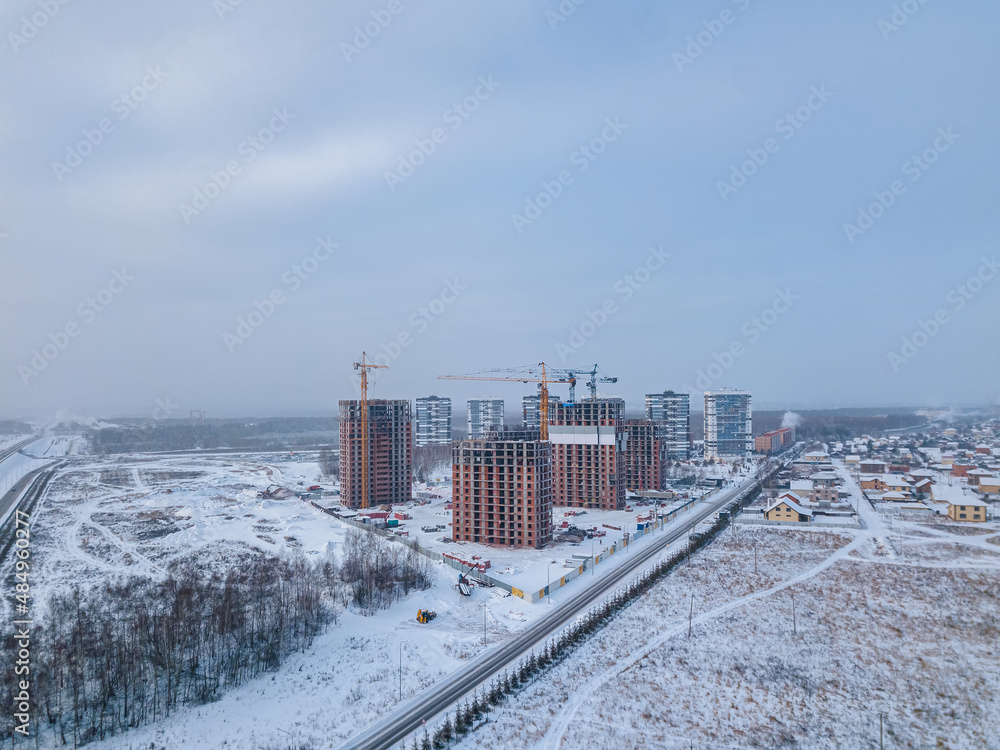 Construction cranes and houses under construction. Construction of a ...