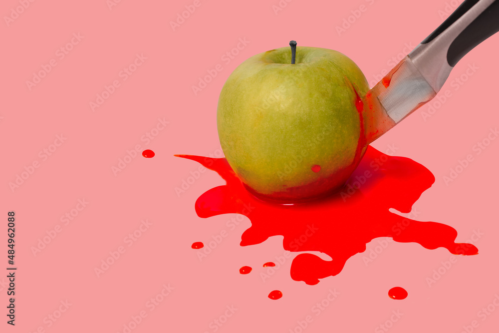 A knife cutting a Green apple and blood flowing, on a pink background ...