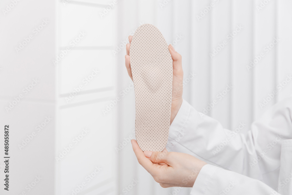 Doctor holding orthopedic insoles in his hands. Orthopedist tests the ...