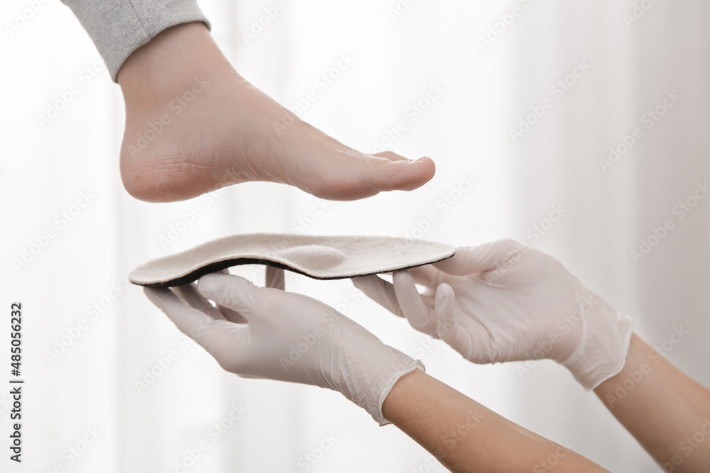 Orthopedic insole on a white background. Hands in rubber gloves hold an ...
