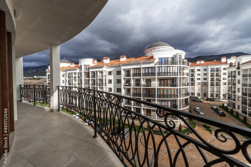 A wide curved balcony of a multi-storey building with metal black ...