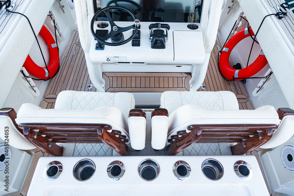 The cockpit of a luxury motorboat, with white leather seats, lifebuoys ...