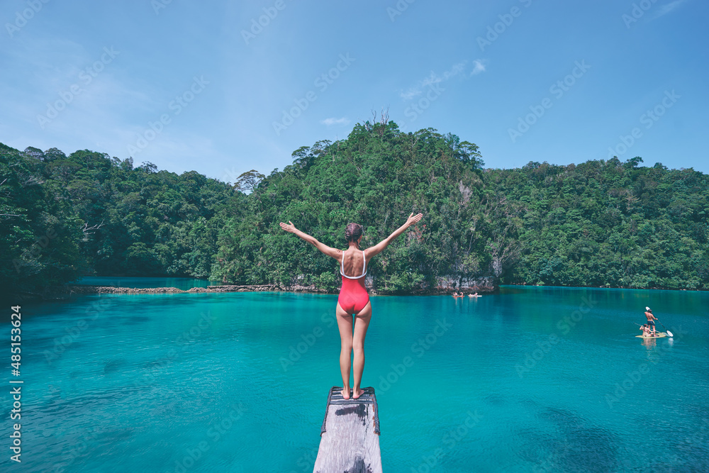 Vacation and activity. Young woman in swimsuit enjoying blue tropical ...