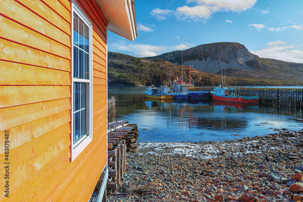 A vibrant orange color boathouse with a wooden pier for fishing. It's a ...