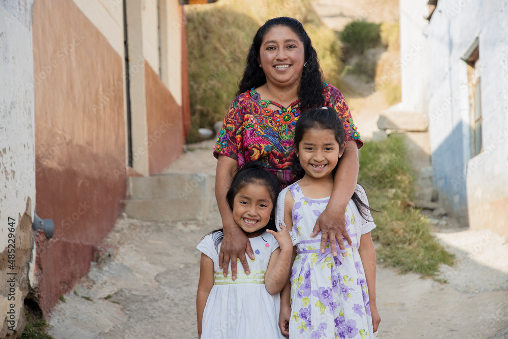 Latin mother with her two happy daughters outside her house in rural ...