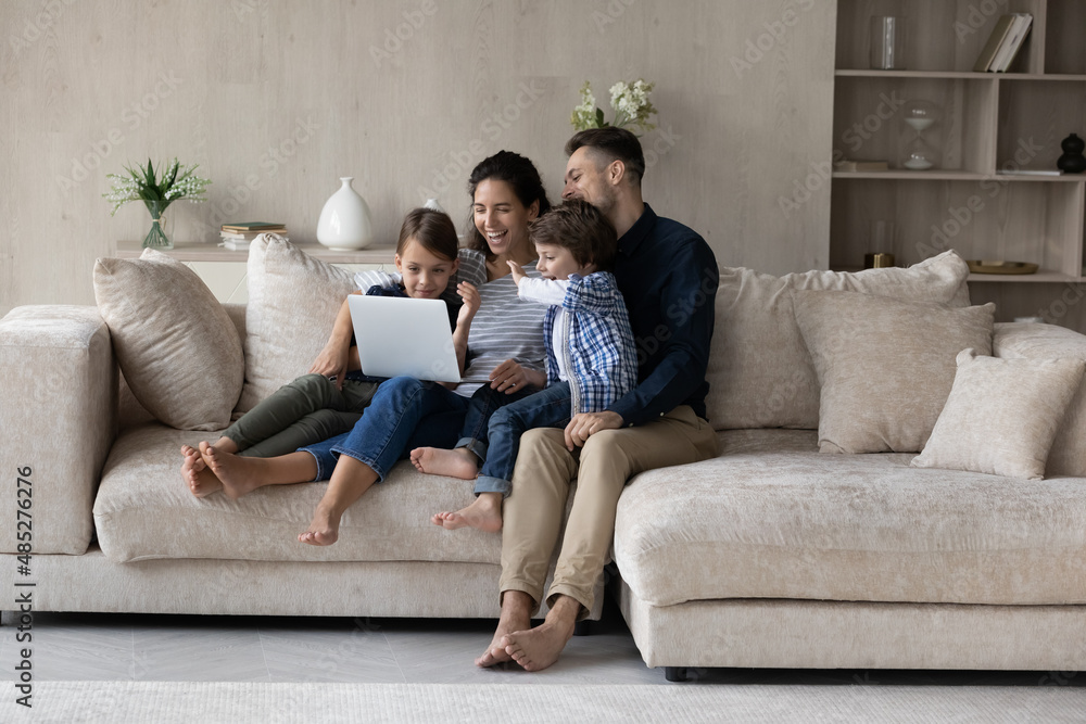 Happy parents with children using laptop, having fun online, sitting on ...