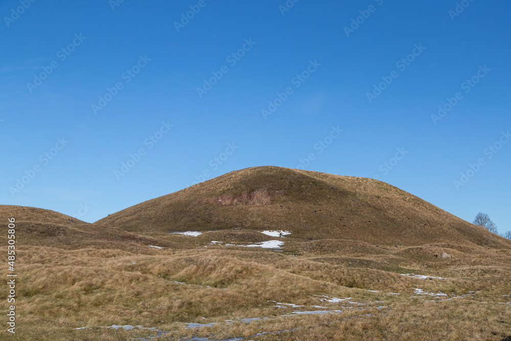 Burial mound covered with grass in rolling hill culture landscape ...