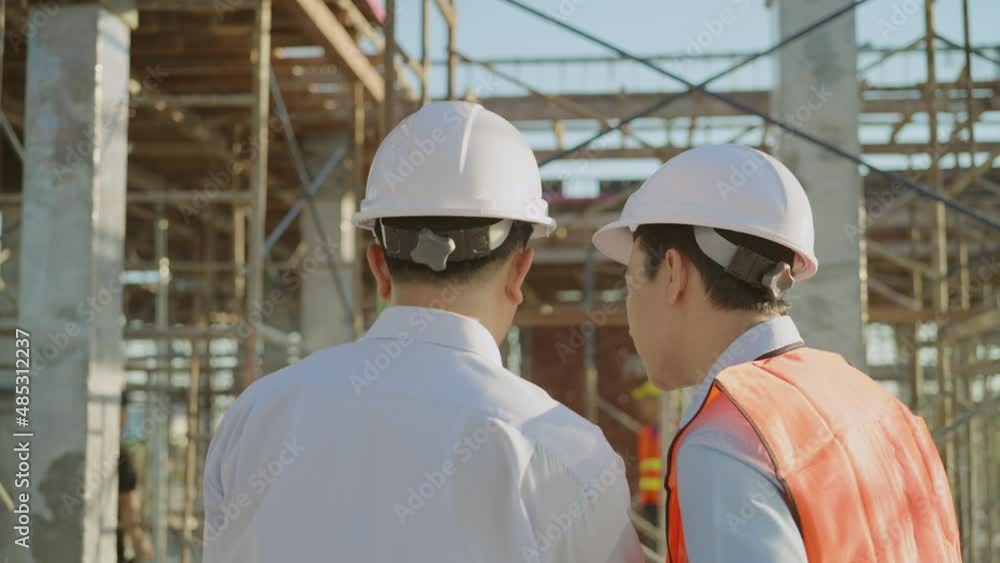 Rear view Engineers and architects in safety uniforms and hard hats ...
