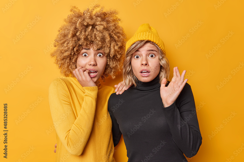 Stressed nervous two women look embarrassed at camera bite finger nails ...