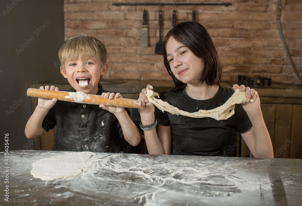 brother and sister roll out cookies from the dough and indulge in flour ...