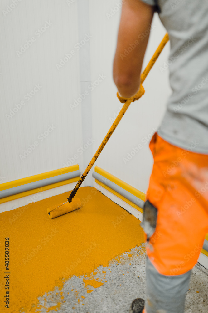 epoxy flooring applicator performs painting works with polyurethane ...