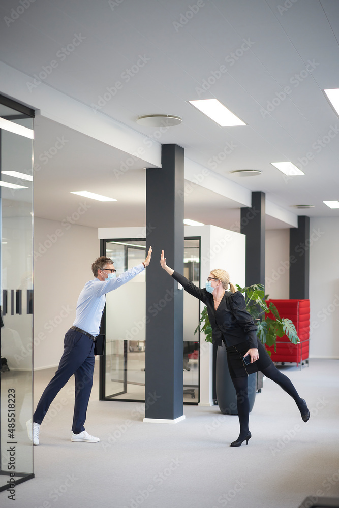 Businessman and businesswoman giving high-five and maintaining social ...