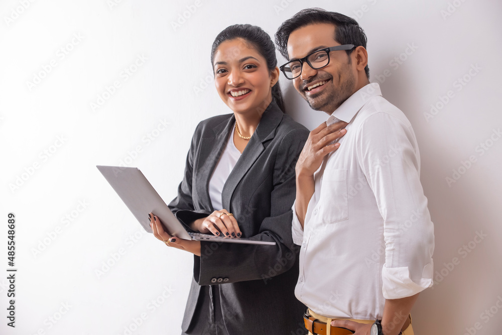 Office colleagues smiling together while doing office work using laptop ...