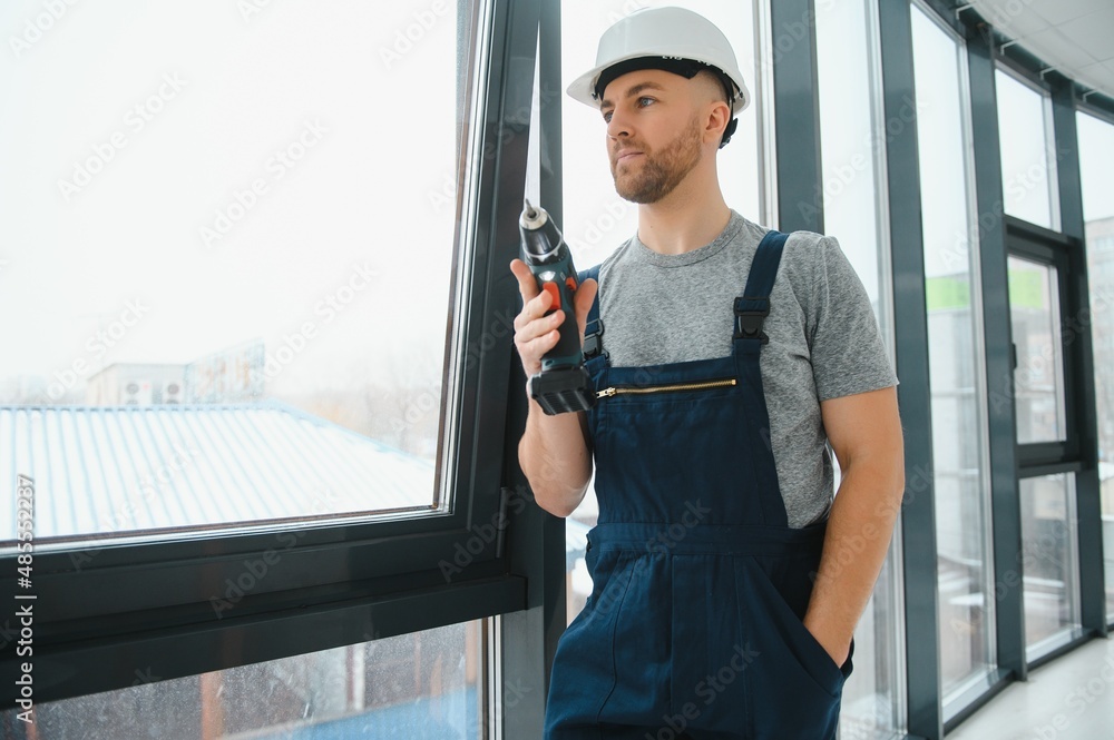 handsome young man installing bay window in new house construction site ...
