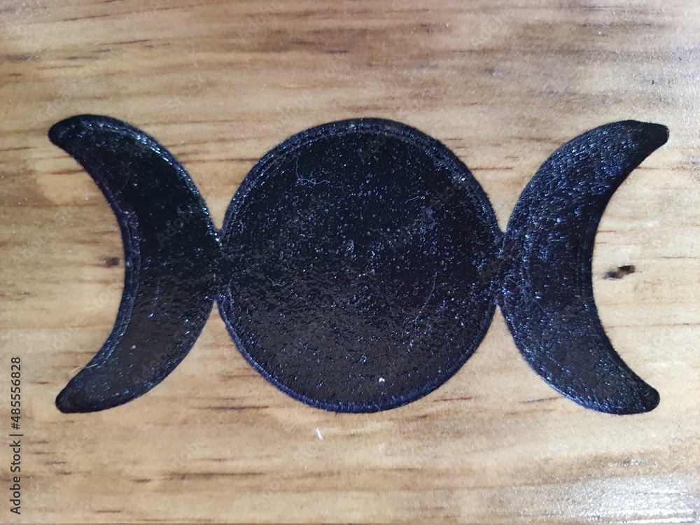Symbol of the triple goddess, moon phases, carved on a wooden surface ...