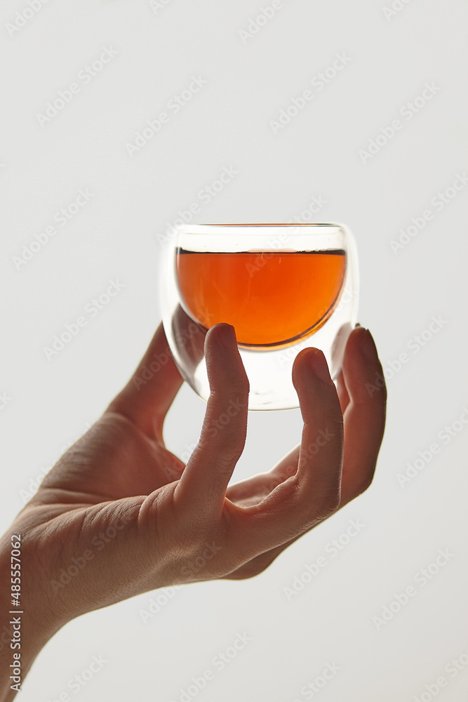 Shot of a female hand holding a small transparent thick-walled glass ...