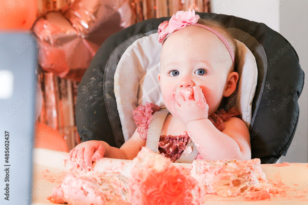 Cute birthday girl celebrating her one year birthday by messily eating ...