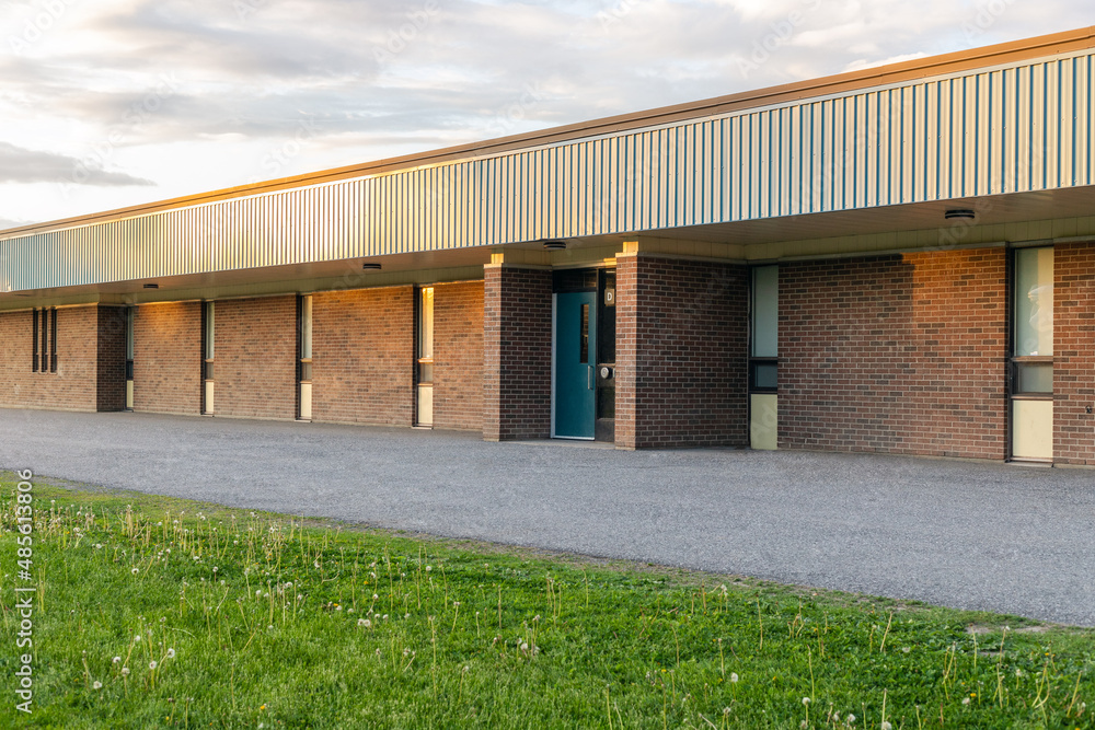 School building exterior and schoolyard with green grass in front on a ...