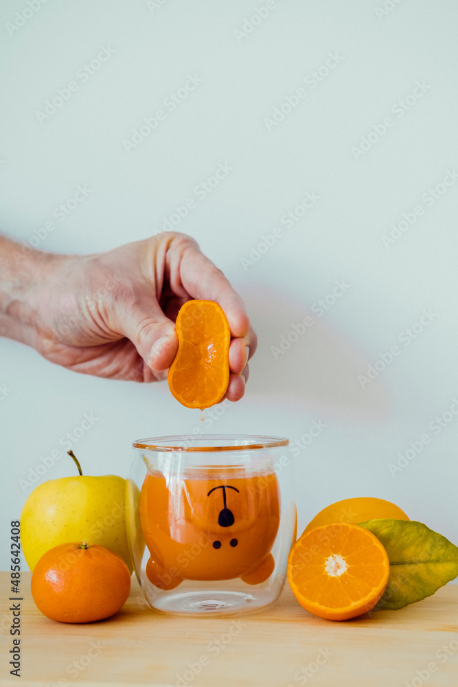 Man hand squeezing a citrus fruit into a funny glass for a child ...