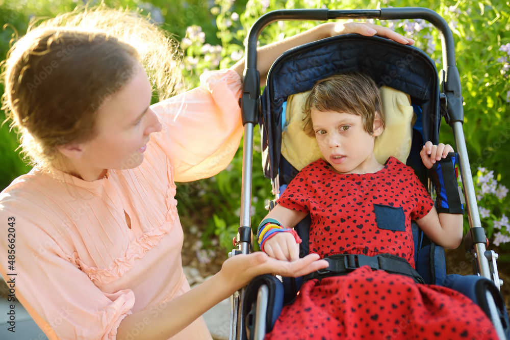 Foto de Woman with disabled girl in a wheelchair walking in the summer ...