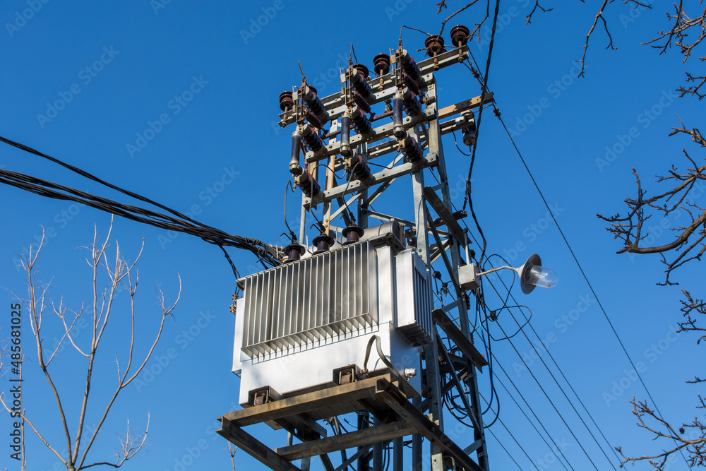 Electric pole with high voltage transformer against the blue sky and ...