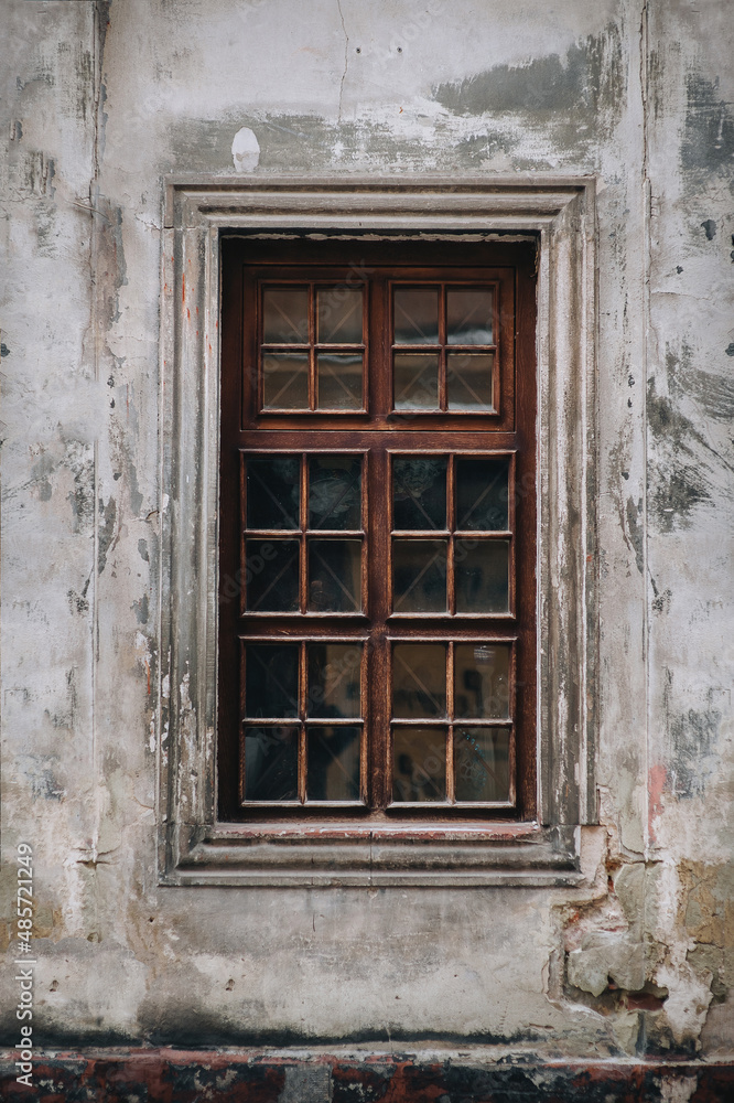 Vintage brown wooden window with square glasses. Cracked wall plaster ...