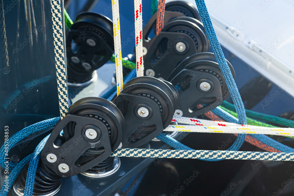 Part of the mast and hull of a sailing yacht, with multi-colored ropes ...