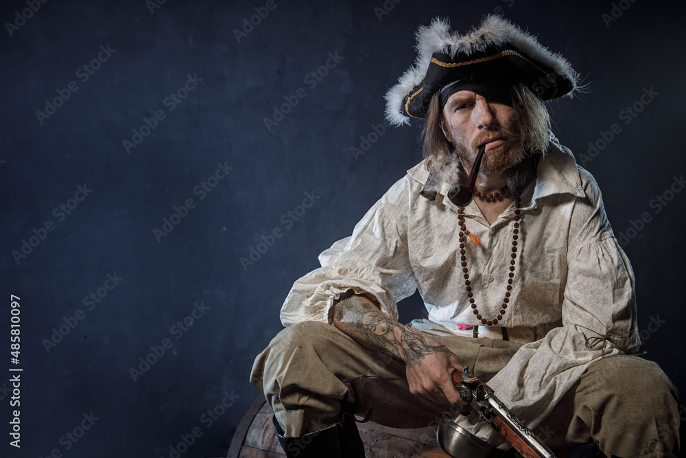 Pirate filibuster sea robber in suit with gun and saber sits on barrel ...