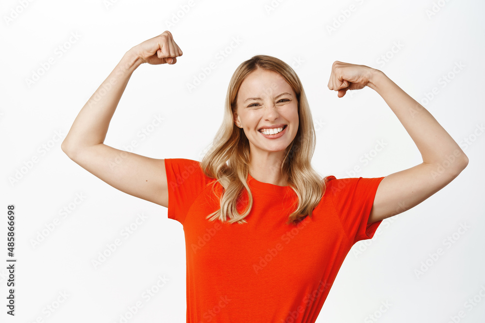 Strong women. Happy young smiling fit girl, showing muscles, raising ...
