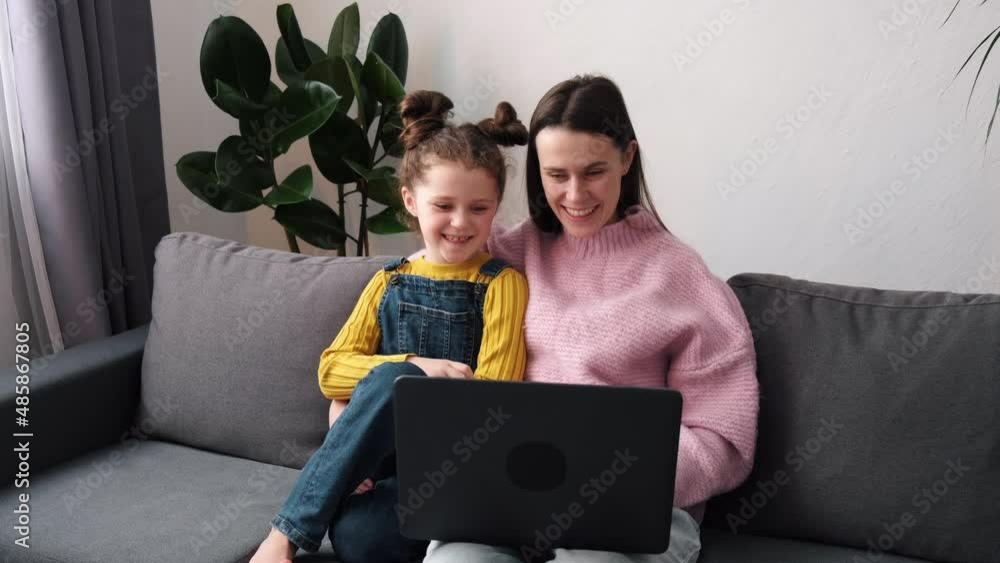 Smiling mom and little child girl looking talking to webcam chatting ...